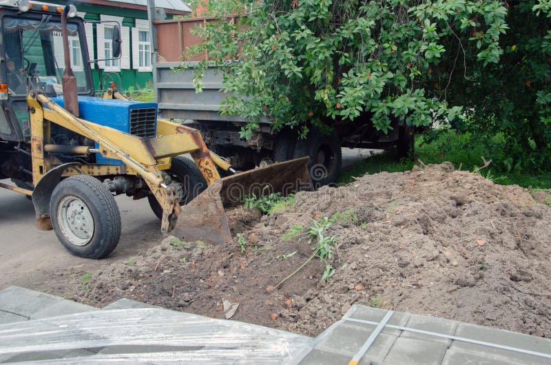 An Excavator is Loading Earth into a Dump Truck, Which is Heavy ...