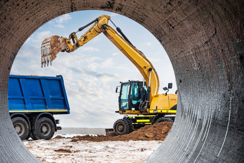 An Excavator Loads Soil or Sand into a Dump Truck. Pit Development ...
