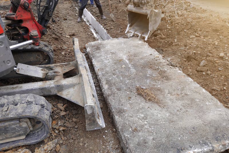 The Excavator Puts Concrete Slabs for Moving through the Gutter ...