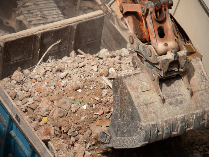 Excavator Removing Debris from a Demolition Site and Dumping it into ...