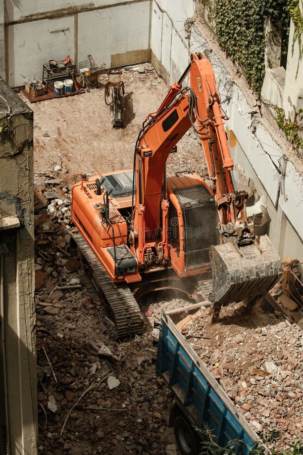 Excavator Removing Debris from a Demolition Site and Dumping it into ...