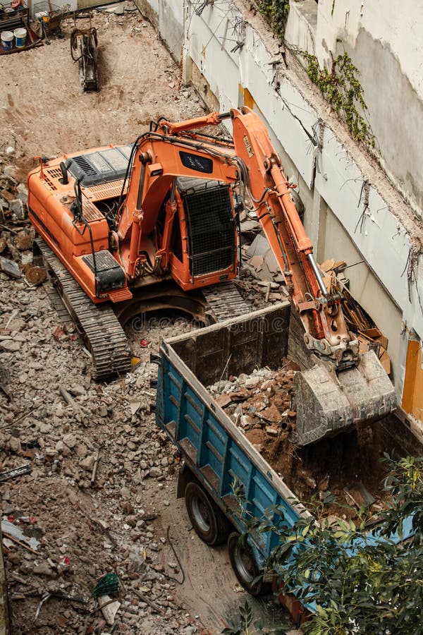 Excavator Removing Debris from a Demolition Site and Dumping it into ...