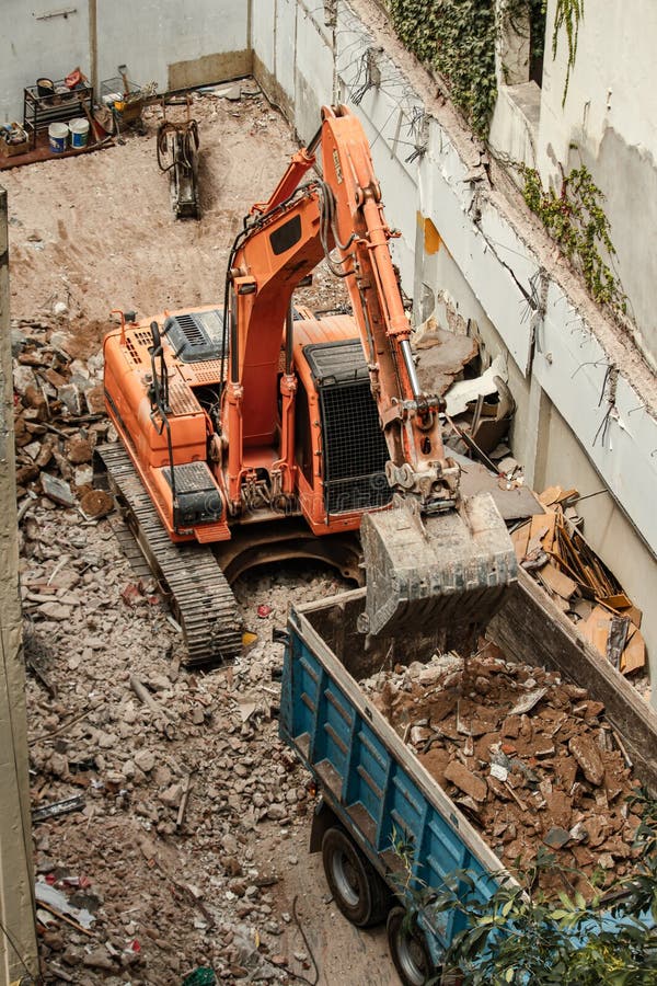 Excavator Removing Debris from a Demolition Site and Dumping it into ...