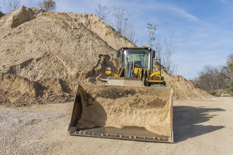An Excavator Stopped in a Work Area with a Mountain of Sand and Gravel ...