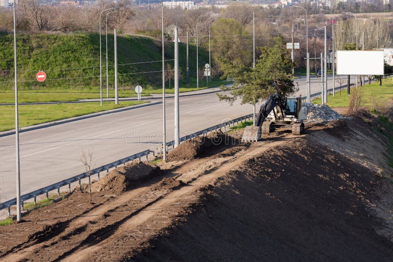 The Excavator Strengthens the Slopes on the Side of the Road. Road ...