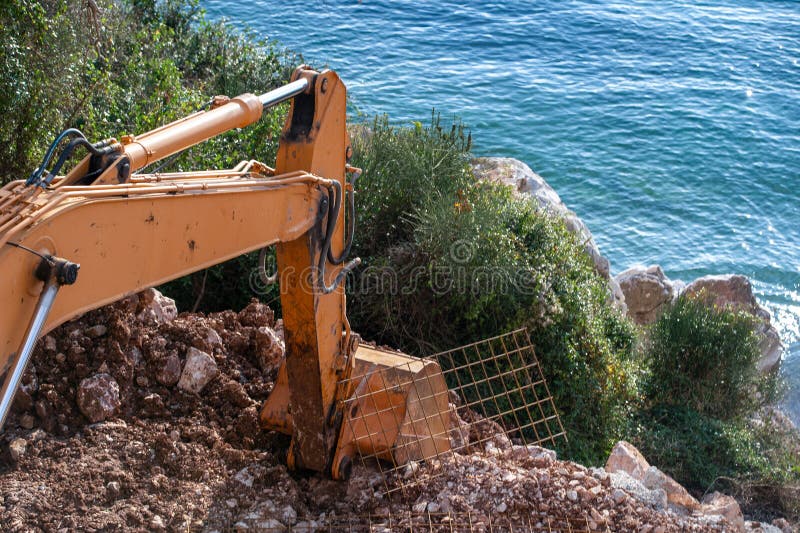 Excavator at Work on a Coastal Construction Site, with Sea in the ...