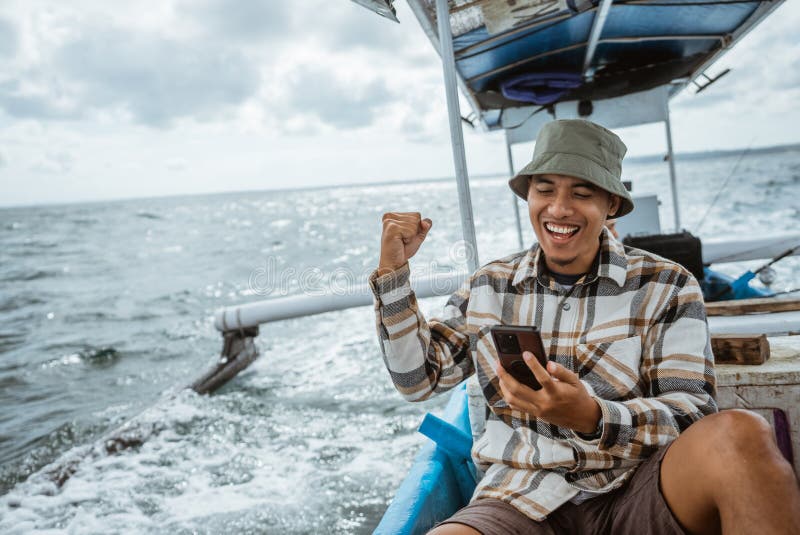Excited Angler Using Cell Phone while Resting on Fishing Boat Stock ...