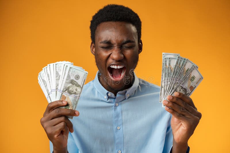 Excited Black Guy Holding Stack of Dollars in Yellow Studio Stock Photo ...