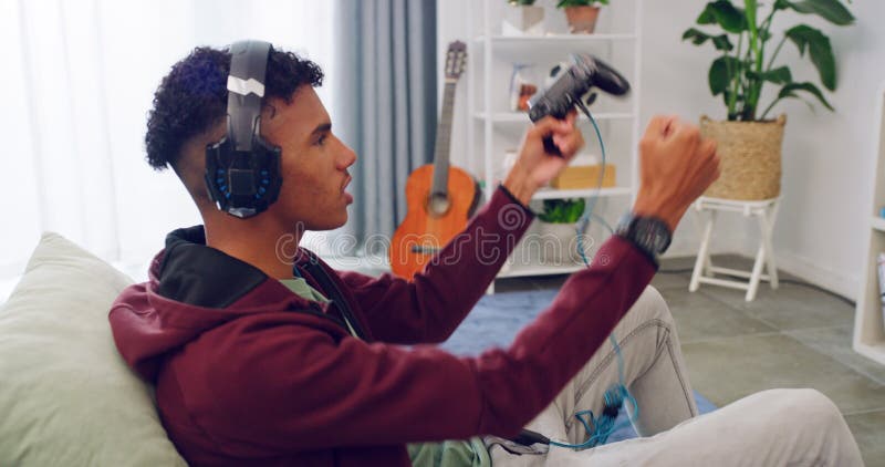 An Excited Gamer is Sitting on a Couch, Playing a Video Game on a ...