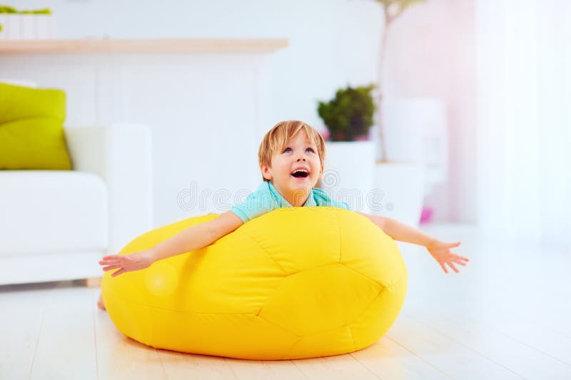 Excited Kid Having Fun on Yellow Bean Bag at Home Stock Photo - Image ...