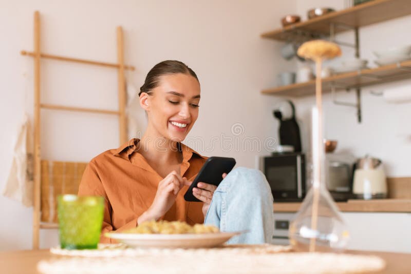 Excited Lady Using Smartphone in Kitchen while Having Dinner, Sitting ...