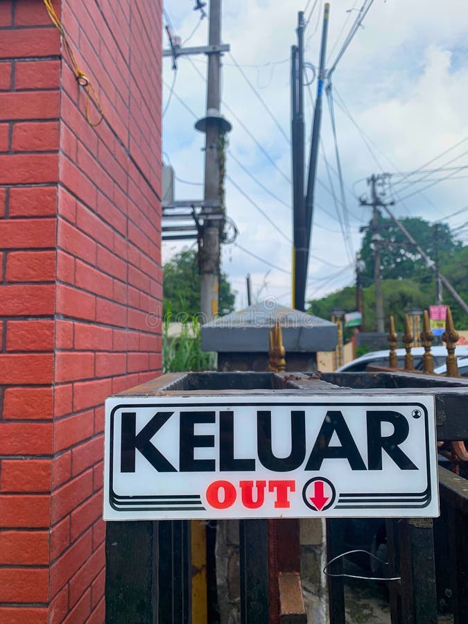 Exit Sign Keluar (Out) on Fence with Red Brick Wall and Utility Poles ...