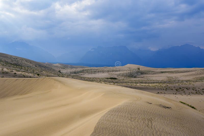 Expansive Desert Dunes Under a Dramatic Sky with Distant Mountains ...
