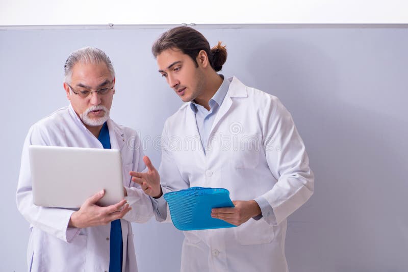 Experienced Doctor Teaching Young Male Assistant Using Computer Stock ...