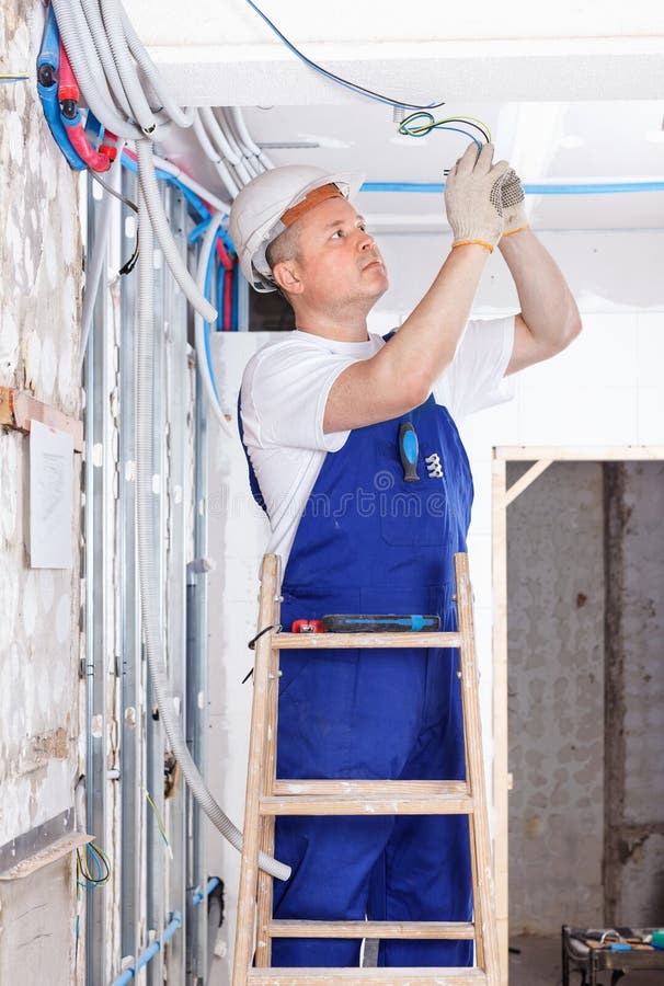 Experienced Electrician Laying Electric Wires in Building Under ...