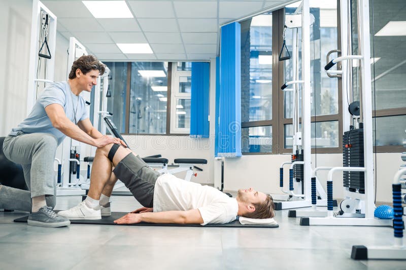 Experienced Instructor Assisting a Man in a Rehabilitation Workout ...