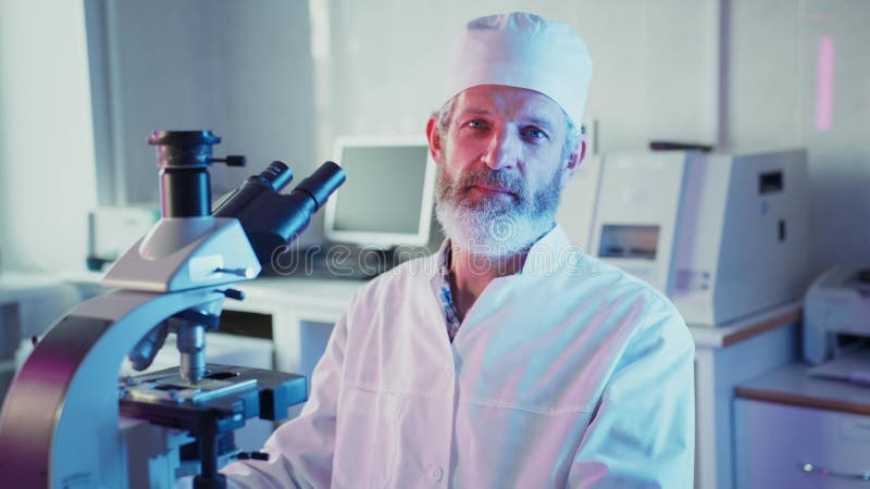 Scientist Adjusting Microscope and Looking at Camera in Laboratory ...