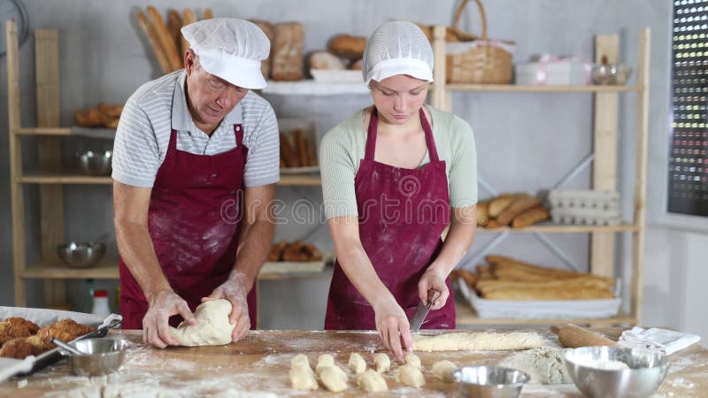 Experienced Older Baker and Young Female Apprentice in Striped Aprons ...