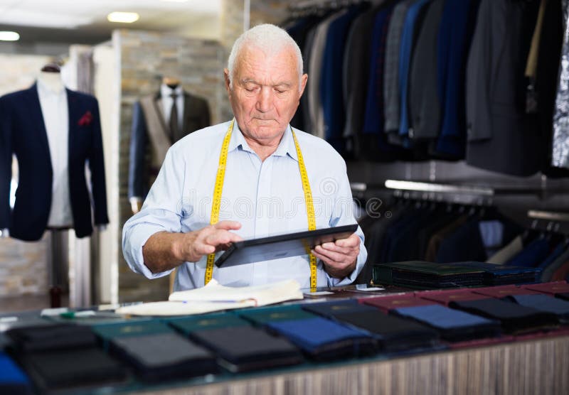 Experienced Tailor Looks at a Pattern on a Tablet Screen in Sewing ...