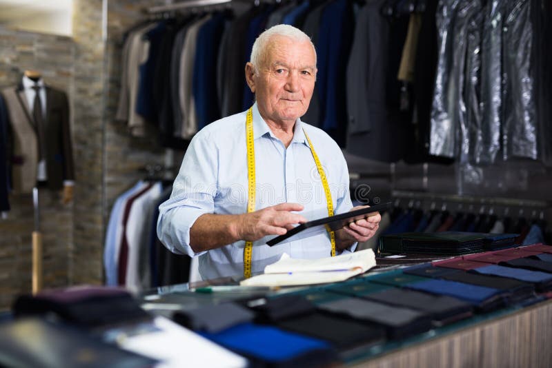 Experienced Tailor Looks at a Pattern on a Tablet Screen in Sewing ...