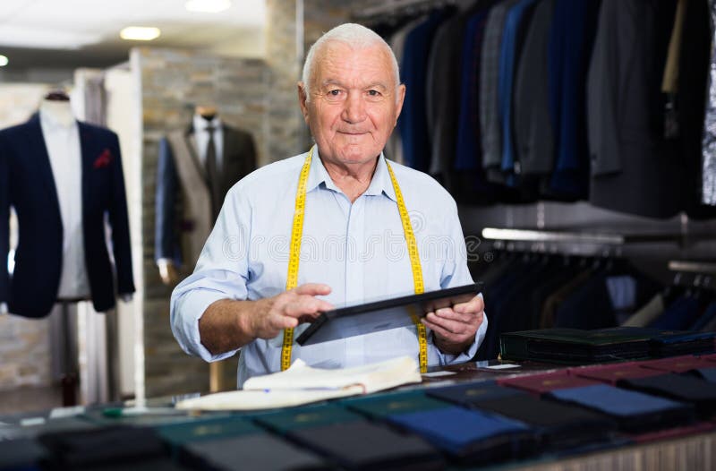 Experienced Tailor Looks at a Pattern on a Tablet Screen in Sewing ...