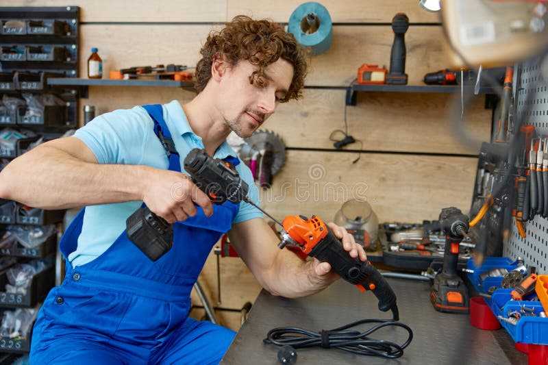 Experienced Young Repairman Fixing Angle Grinder Power Tool at Workshop ...