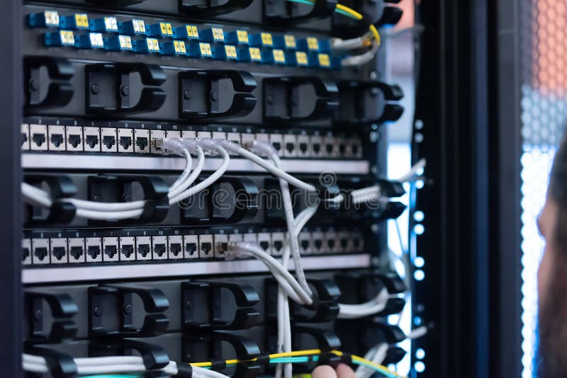 An Expert Engeneer in Datacenter Server Room Connecting Cables in Server Cabinet in Network ...