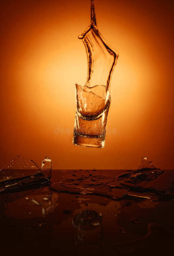 Exploding Glass Cup with Water Shattering Over Orange Background. Stock ...