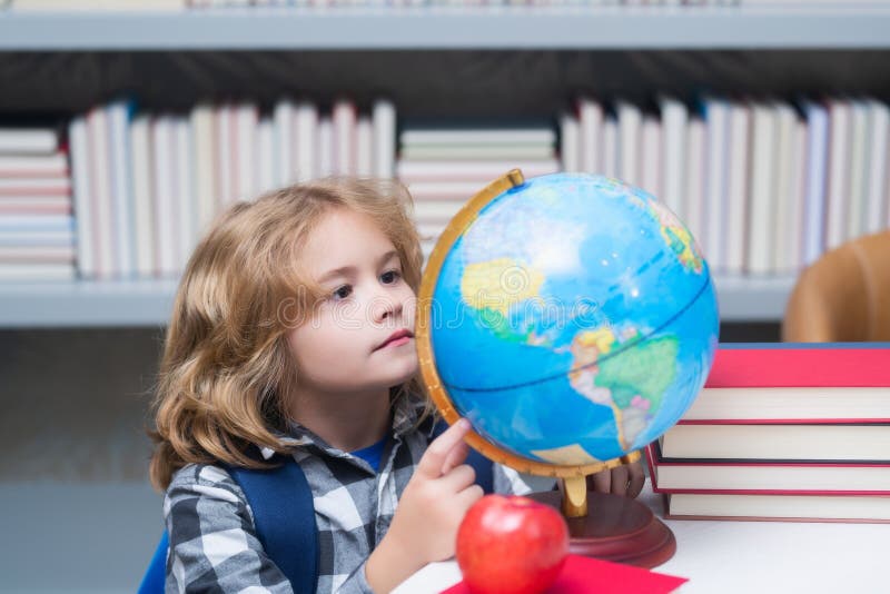 Explorer and Discovery. School Kid Pupil Looking at Globe in Library at ...