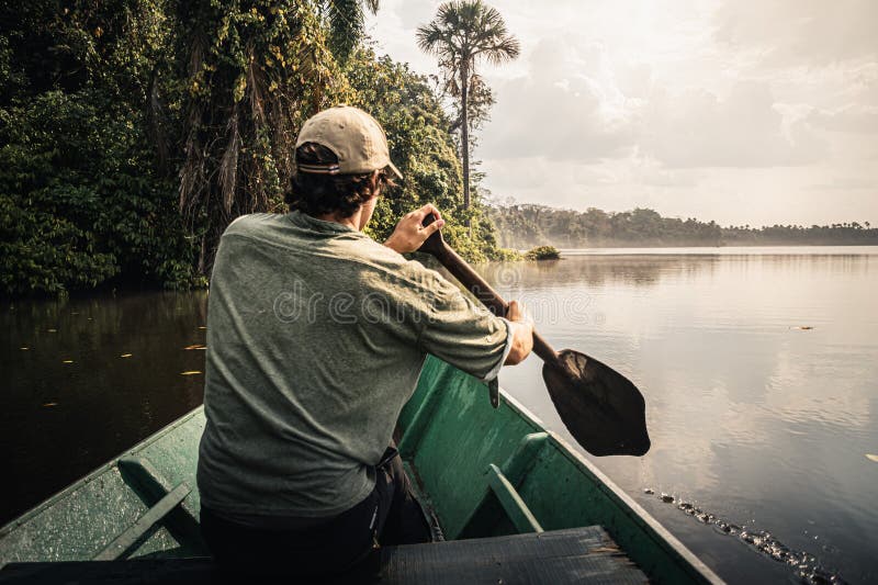 Explorer Paddling a Canoe on the Amazon River at Sunset Stock Photo ...