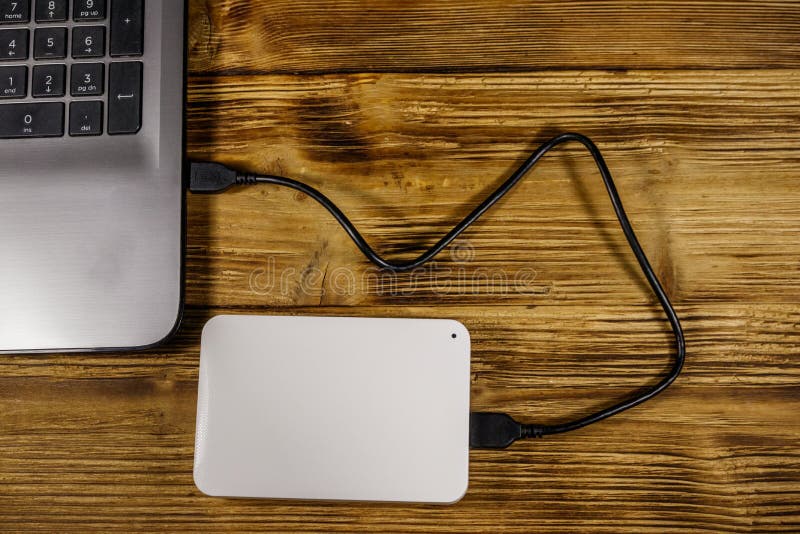 External HDD Connected To Laptop Computer on Wooden Desk. Top View ...
