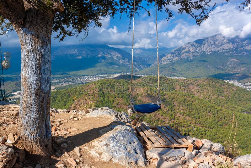 Extreme Swing on Edge of High Mountain with View of Mountains in Clouds ...