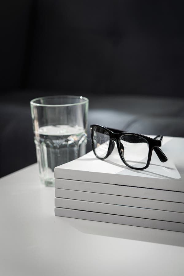 Eyeglasses with Stack of Books, and the Glass of Water on the Table ...
