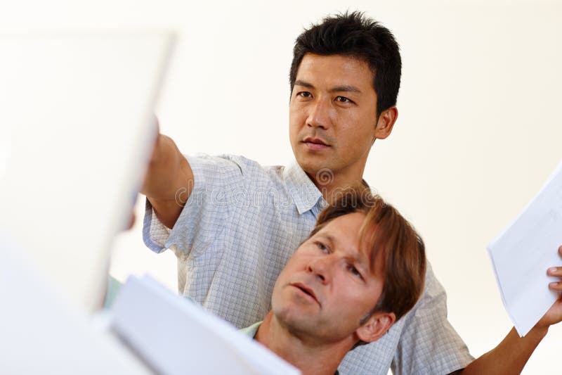 Eyeing the Small Details. Two Men Looking Over a Document in an Office ...