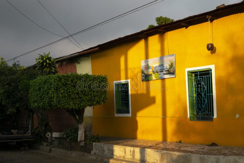 Facade of an Old Yellow Building Along the Street with Tree and Stormy ...