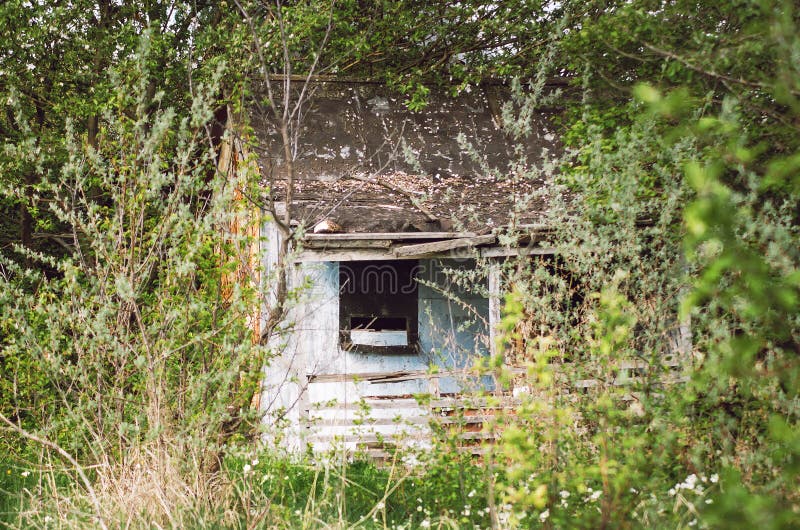 The Facade of a Small Destroyed House with Broken Windows among the ...