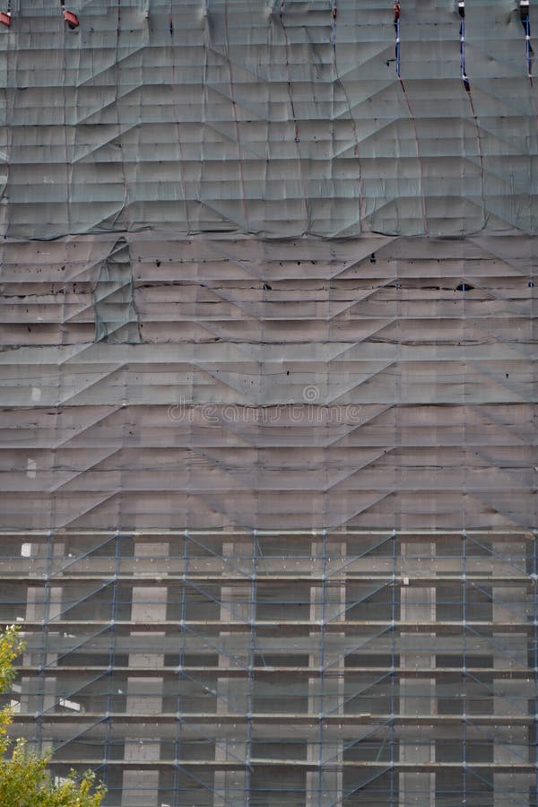 The Facade of a Tall Building Under Construction is Curtained with a ...