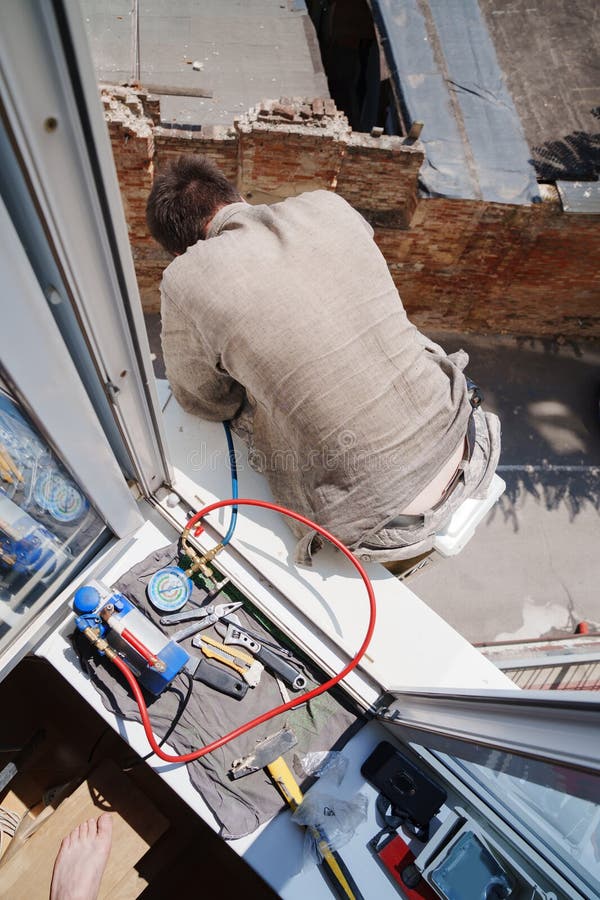 Without a Face. a Man Installs an External Air Conditioner. Dangerous ...