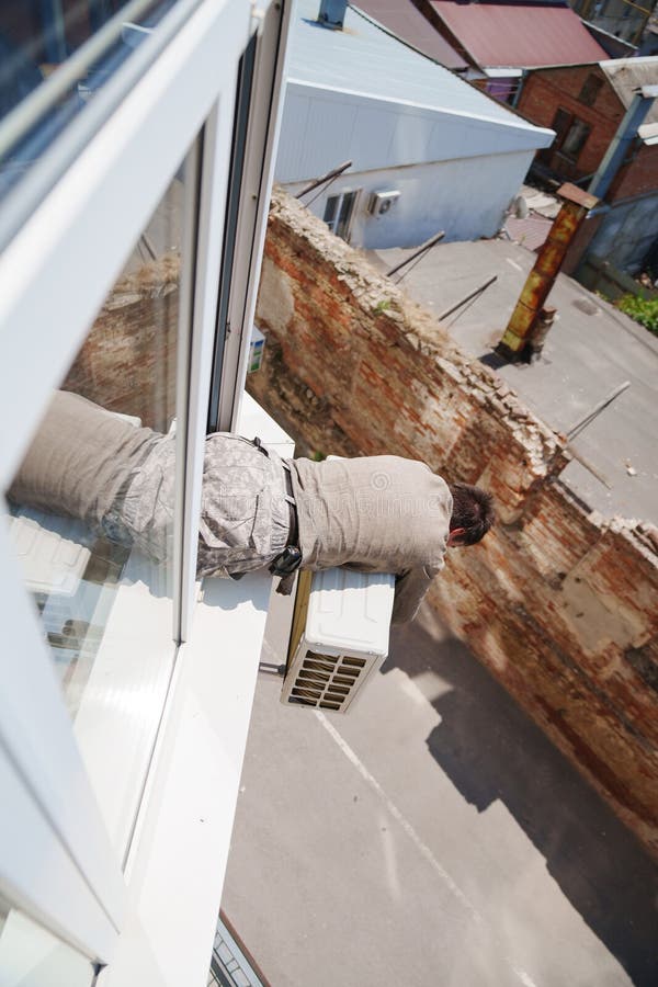 Without a Face. a Man Installs an External Air Conditioner. Dangerous ...
