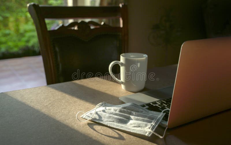 Face Mask Next To Computer Laptop and Cup on Table Stock Photo - Image ...