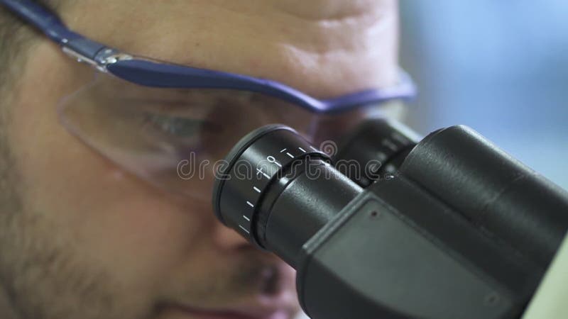 Male Lab Tech Doctor Scientist Looking into Microscope Connected To ...
