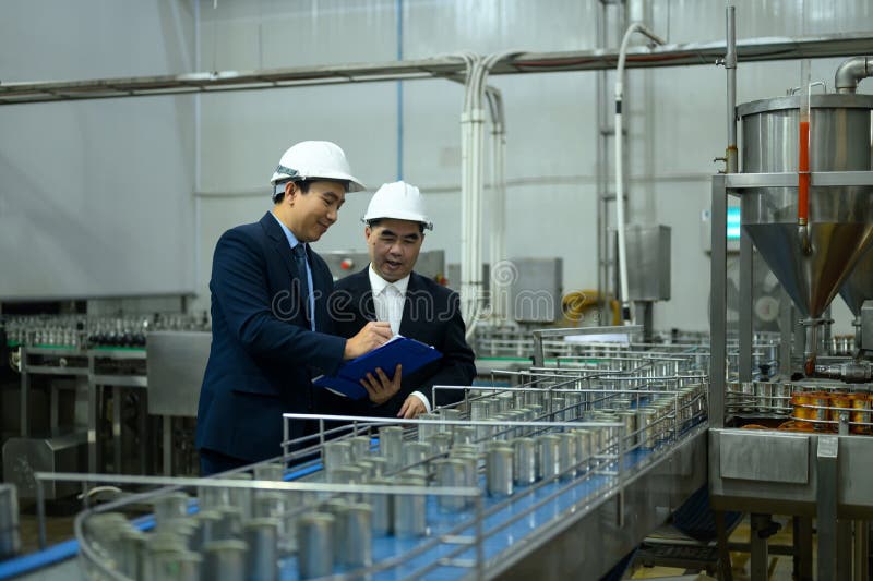 Factory Managers in Hard Hats Discussing Production Plans Inside a Manufacturing Facility Stock ...