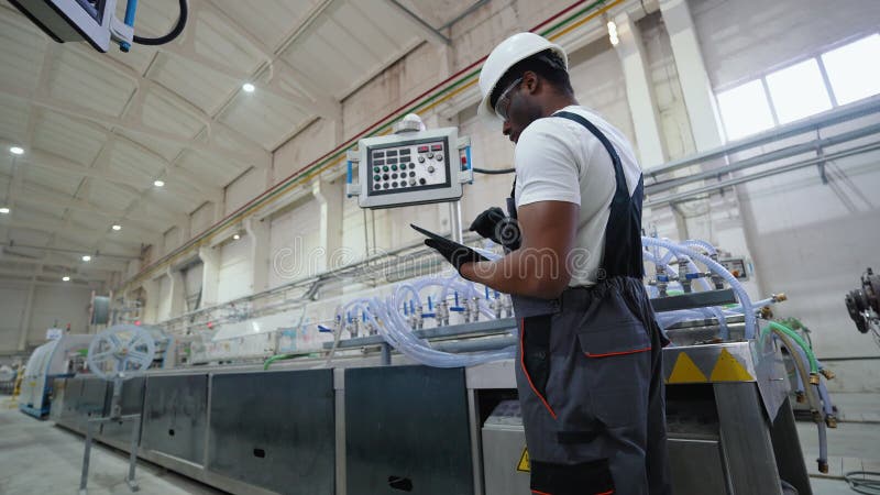 Factory Worker in a Hard Hat and Uniform is Using a Tablet with an ...