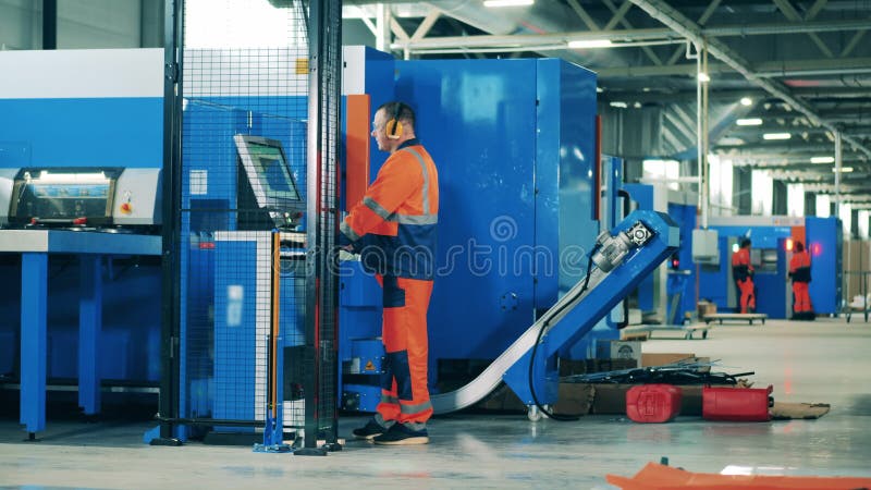 Factory Worker Operating an Industrial Machine on a Modern Assembly ...