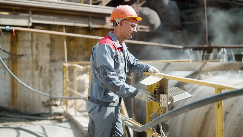 Factory Worker in Safety Gear Operating Machinery in Industrial Setting ...