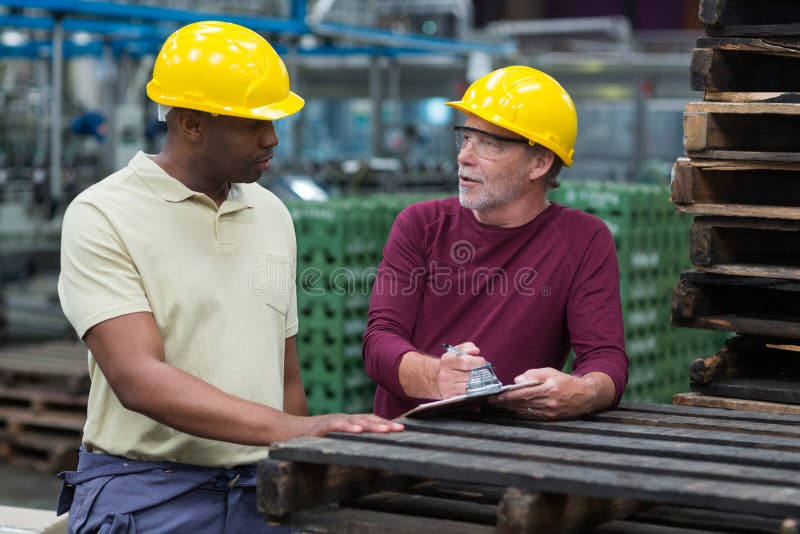 Factory Workers Discussing with a Clipboard in Drinks Production Plant ...