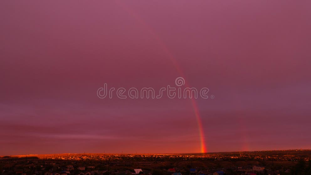Rainbow Arching Across Dramatic Sunset Sky Over Rooftops Stock Image ...