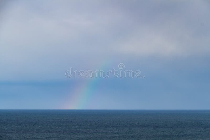 A Faint Rainbow Arching Over the Vast Pacific Ocean Stock Photo - Image ...