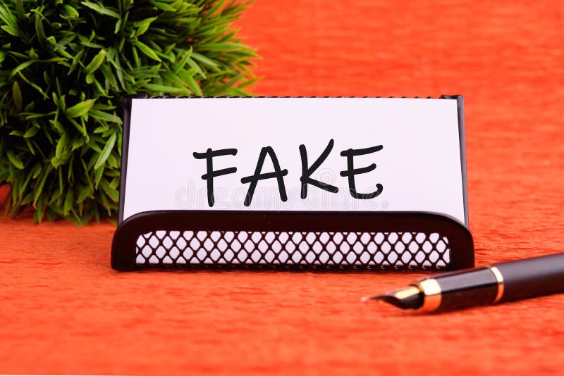 FAKE Word Written on a White Card on a Stand on an Orange Background ...