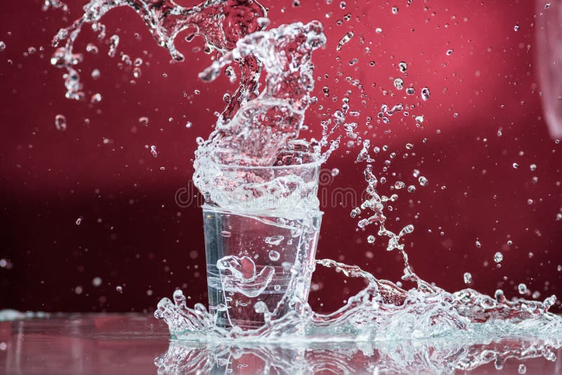 Falling Small Glasses and Spilling Water on a Blue Background Stock ...